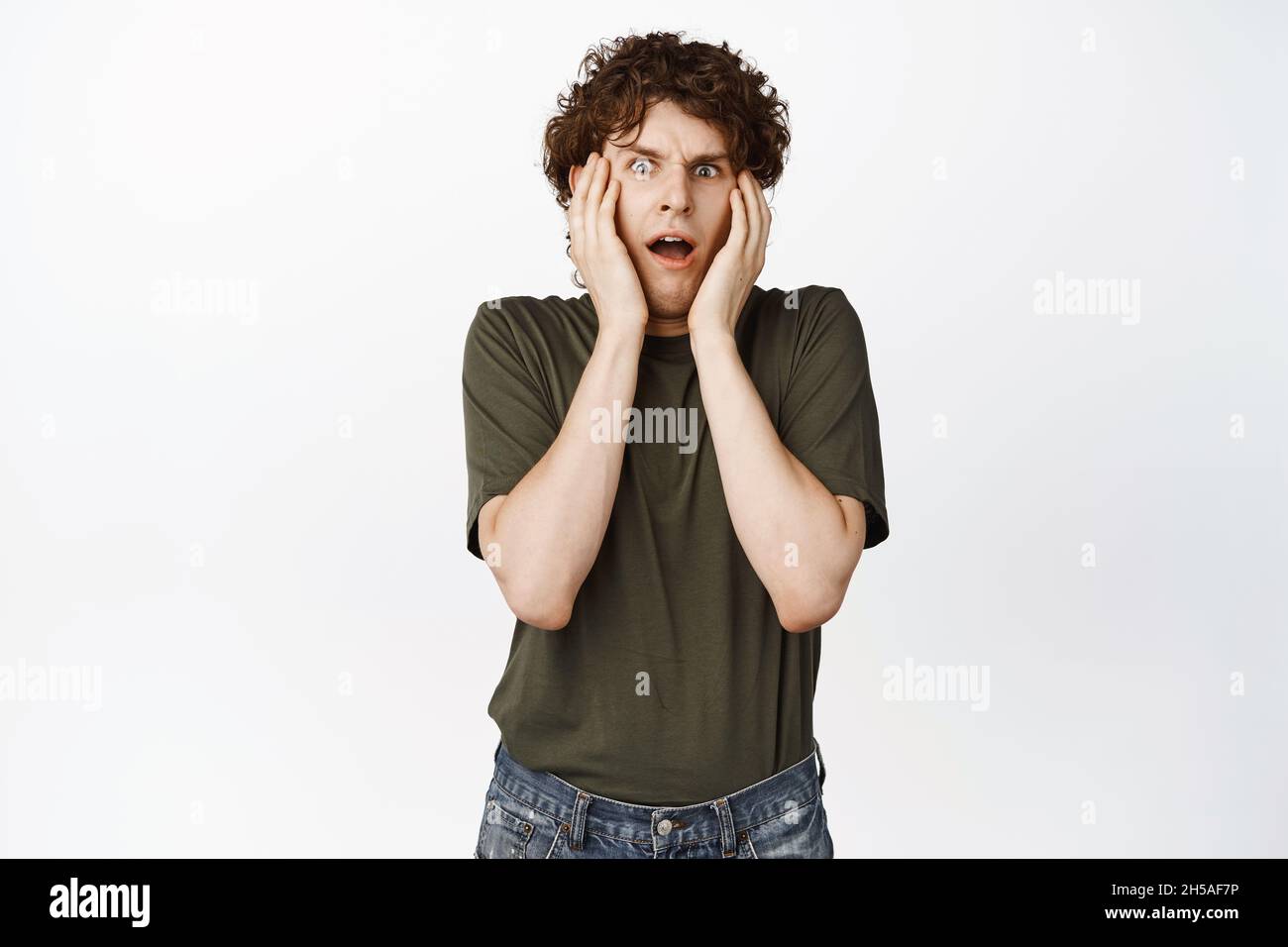 Scared and anxious curly guy freak out, screaming from fear and staring ...