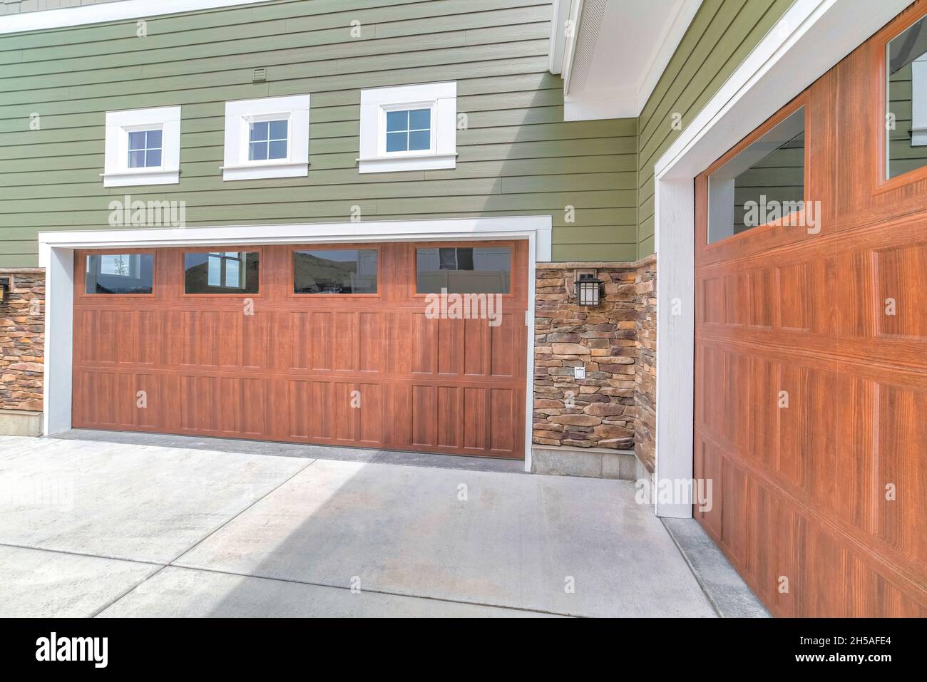 Wooden garage doors with window panels and wall lamp Stock Photo - Alamy