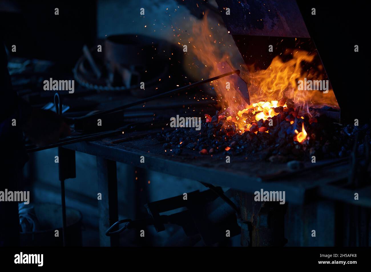 Piece of metal heating under high temperature inside fireplace at forge ...