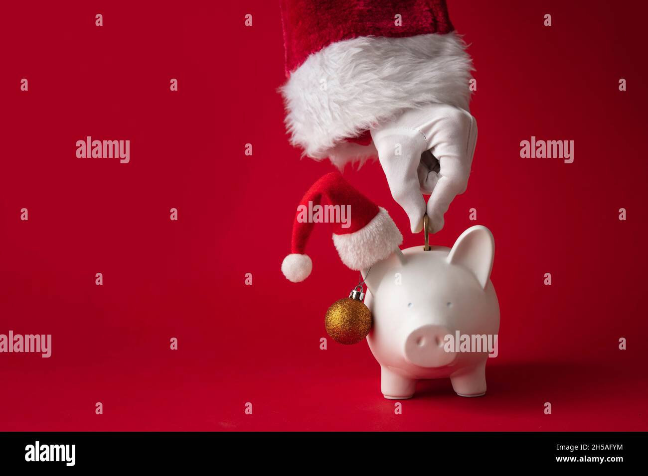 Santa Claus putting money into a Christmas piggy bank money box ...