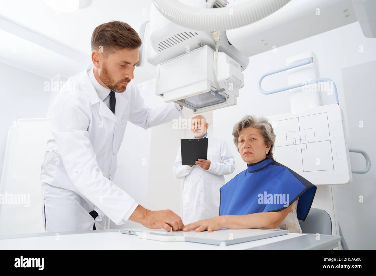 Assistant preparing old female patient in blue robe for diagnostic hand ...