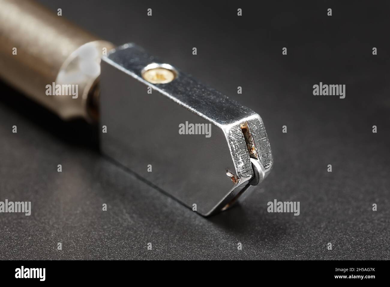 Glass cutter head with cutting roller, close up on dark background ...