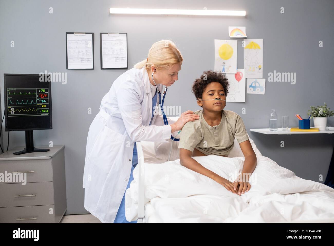 Doctor examining the lungs of little boy with stethoscope during ...
