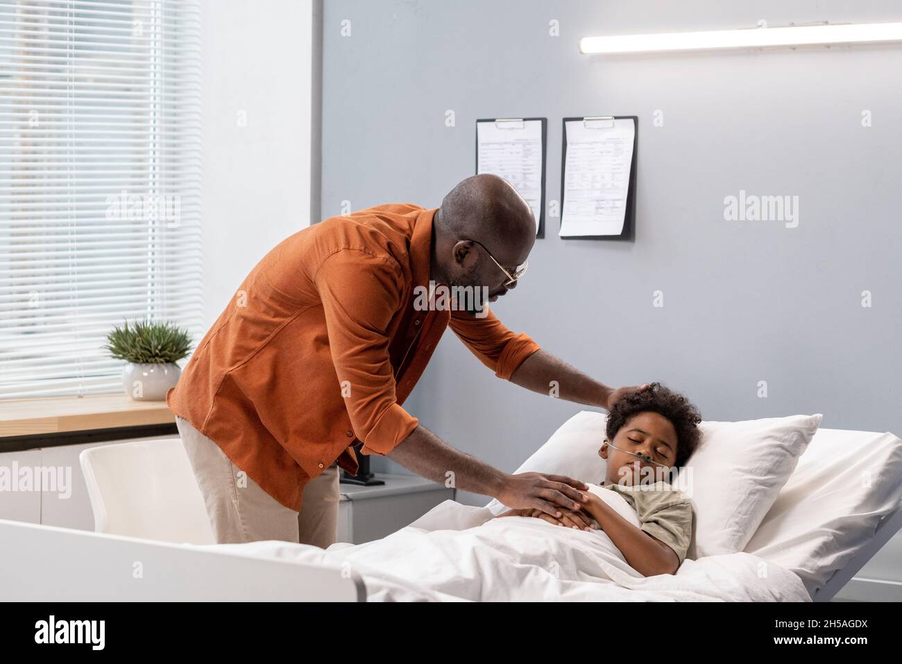 African father caring about his little son while he lying in hospital ...