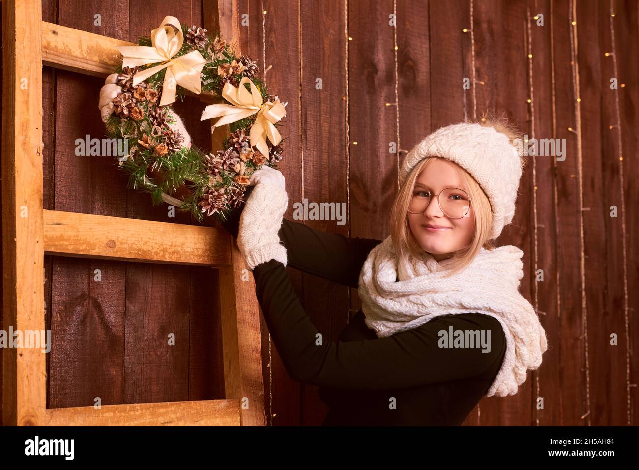 girl with christmas wreath decorate wooden wall. pretty young woman in ...