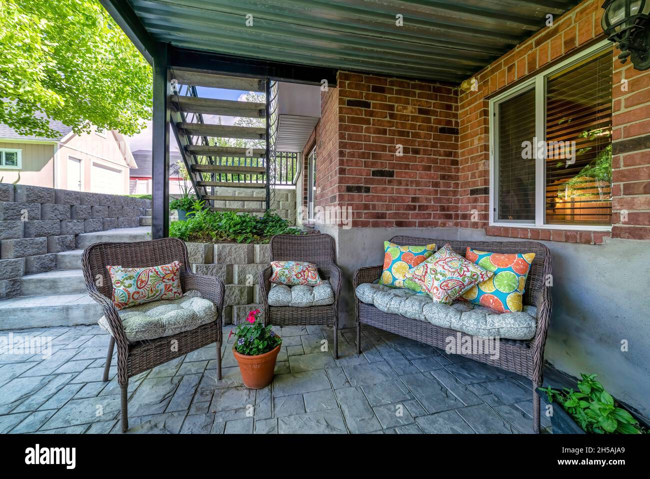 Outdoor patio under a deck with woven lounge chairs and potted plants ...
