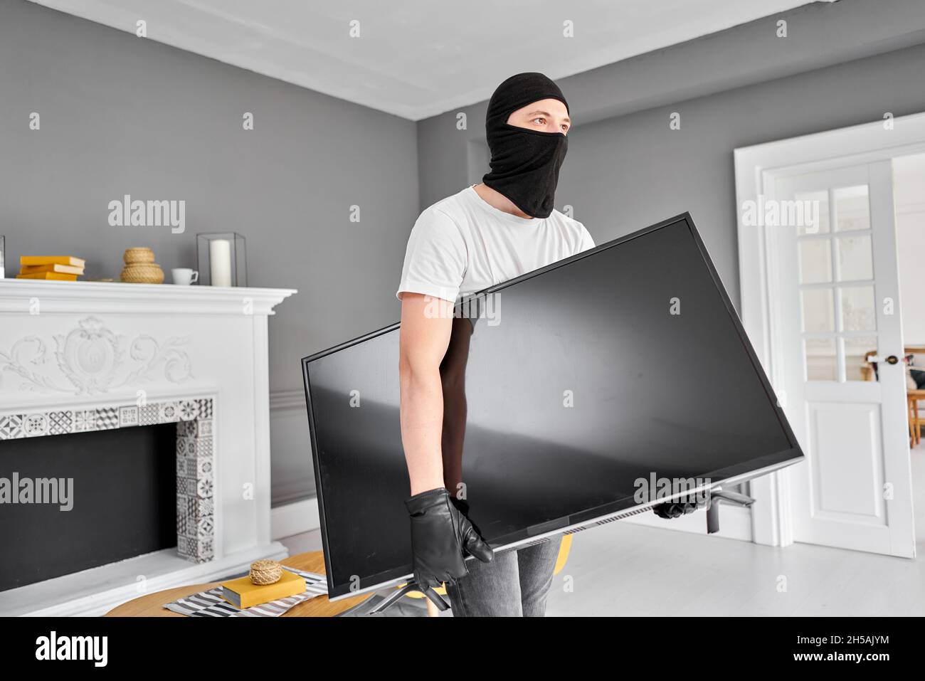 Thief with black balaclava stealing modern expensive television. Masked ...