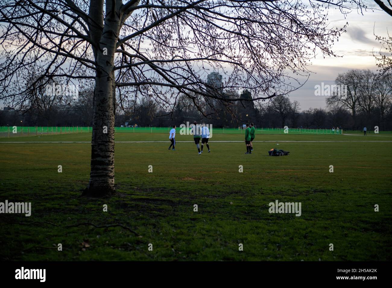 People playing football soccer at dusk in green British park Stock ...