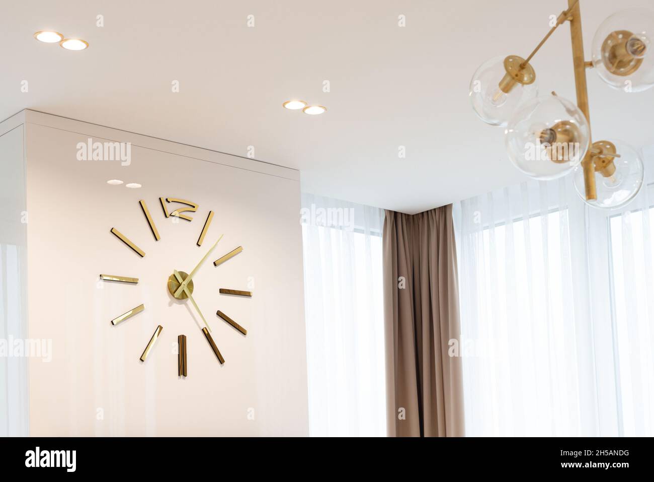 A huge clock in gold color on the wall in a modern beige interior ...
