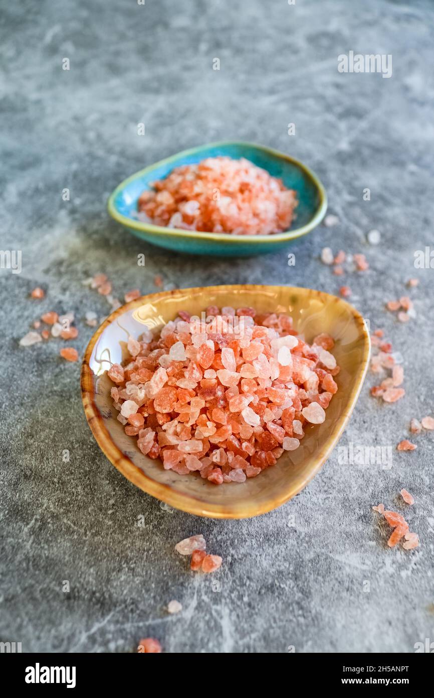 Pink Himalayan rock coarse salt in two small plates on gray background ...
