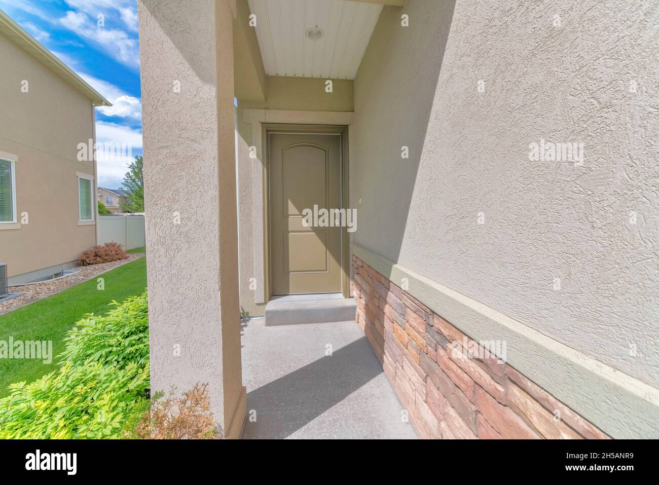 Narrow entrance pathway of a house with a brown cream front door Stock ...