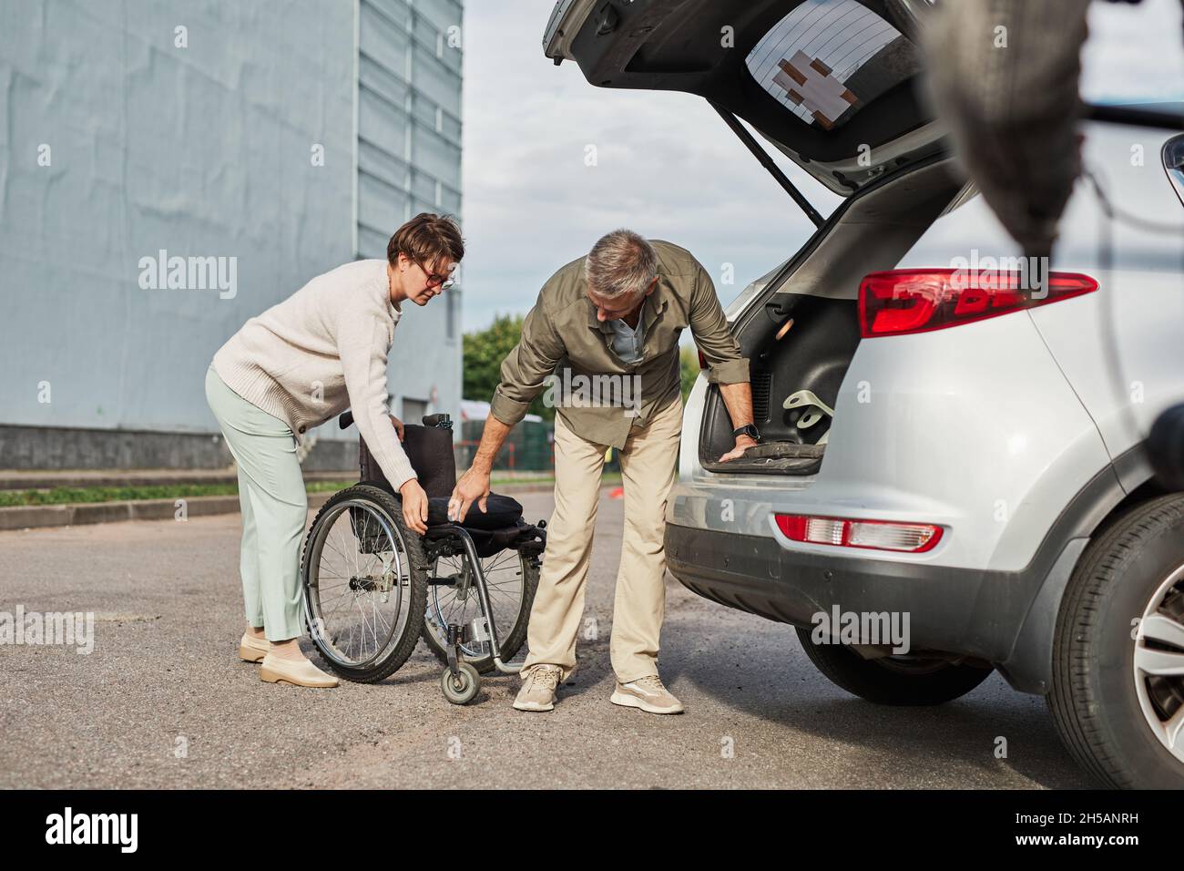 Full length portrait of mature couple unloading wheelchair out of car ...