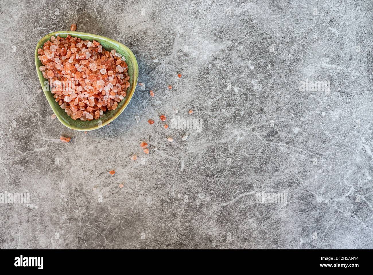 Pink Himalayan rock coarse salt in a green little plate on gray ...