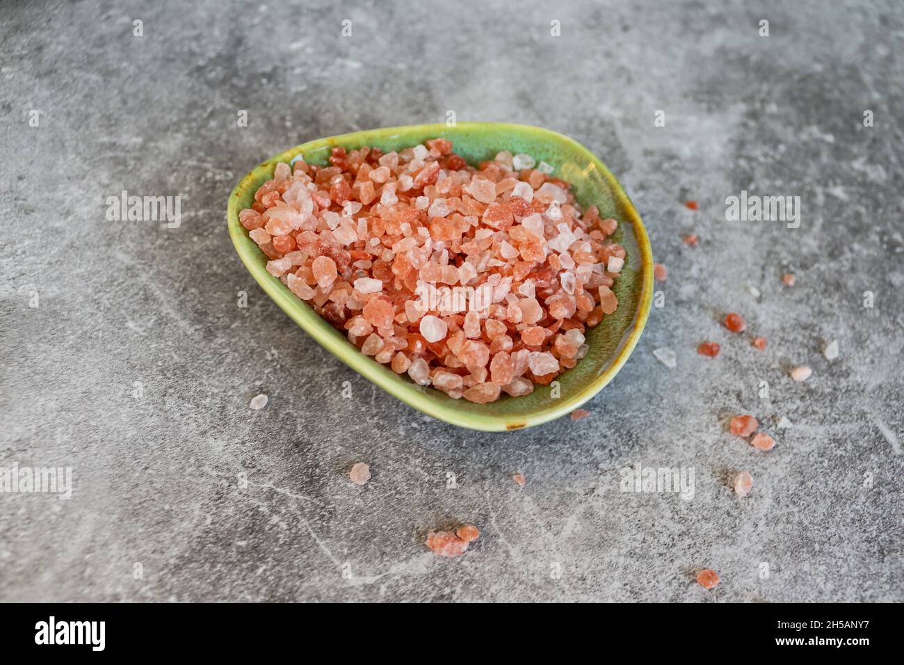 Pink Himalayan rock coarse salt in a green little plate on gray ...