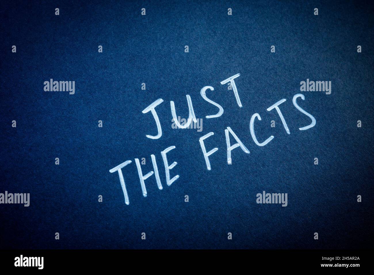 Handwritten words just the facts on the dark surface Stock Photo - Alamy