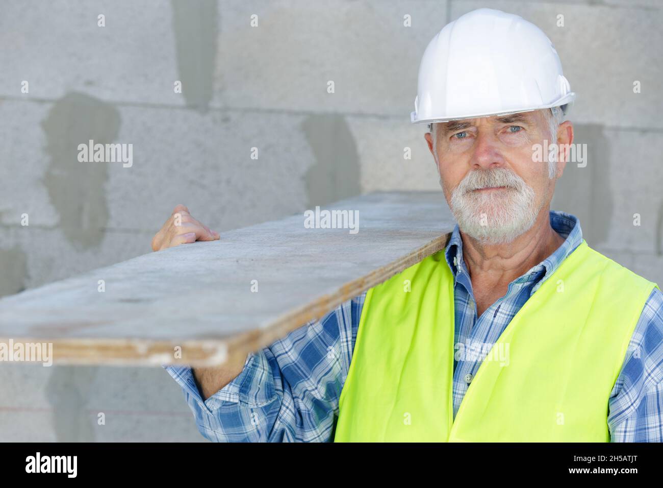 senior worker wearing hard hat and carrying timber Stock Photo - Alamy