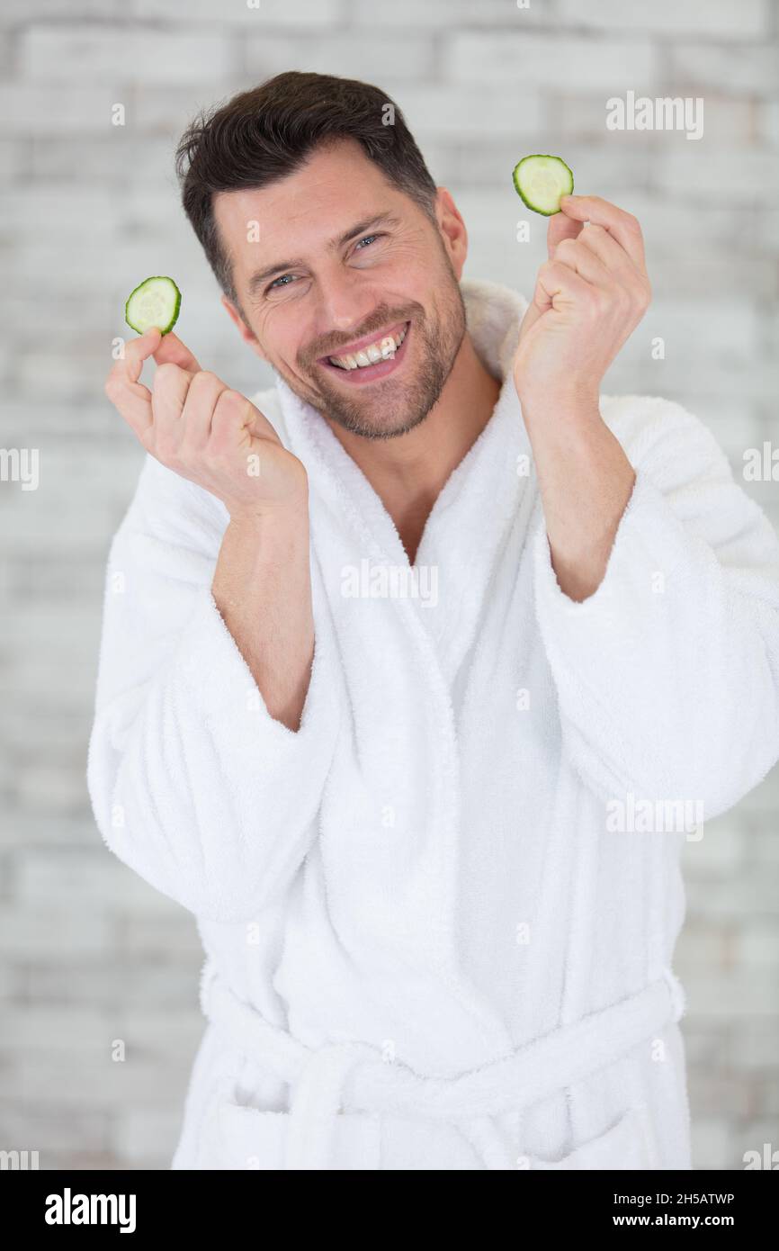man at spa wearing robe holding cucumber slice Stock Photo - Alamy