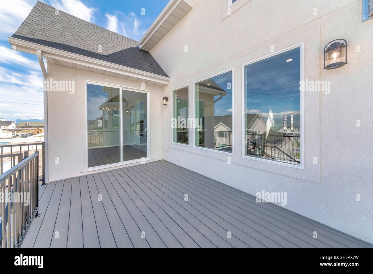 Deck of a house with reflective sliding glass door and picture windows ...