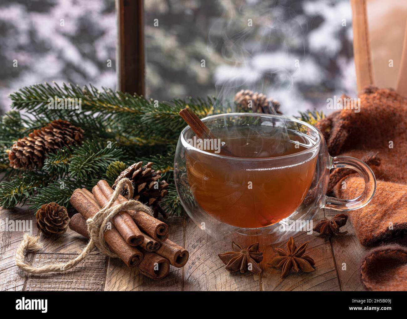 Steaming hot cup of tea on a wooden table by a window with winter ...