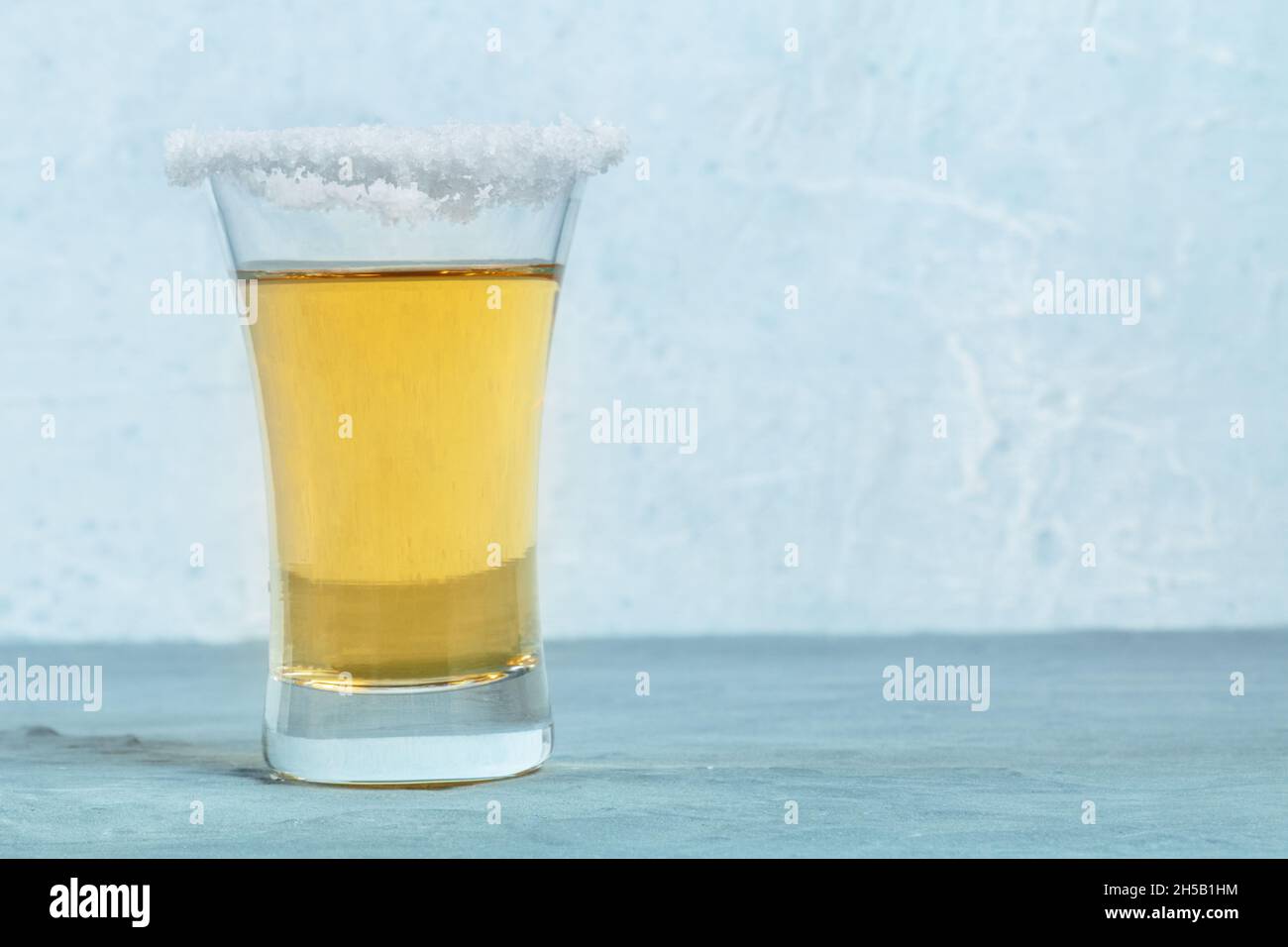 Gold tequila shot with a salted rim, a Mexican drink, side view with ...
