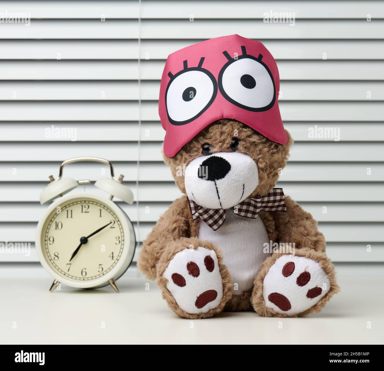 brown teddy bear sits with a bandage for sleeping on a white table ...