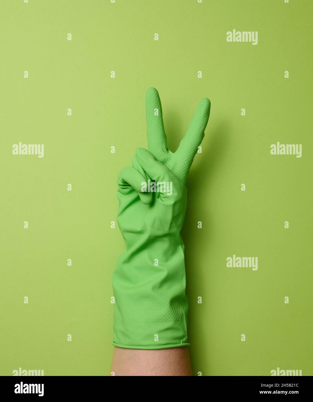 hand in a rubber green glove for cleaning on a green background, part ...
