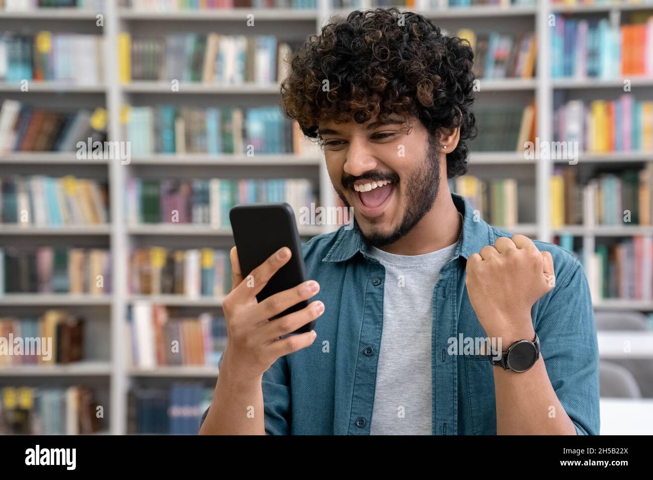 Excited student is happy holding mobile phone and cheering standing in ...
