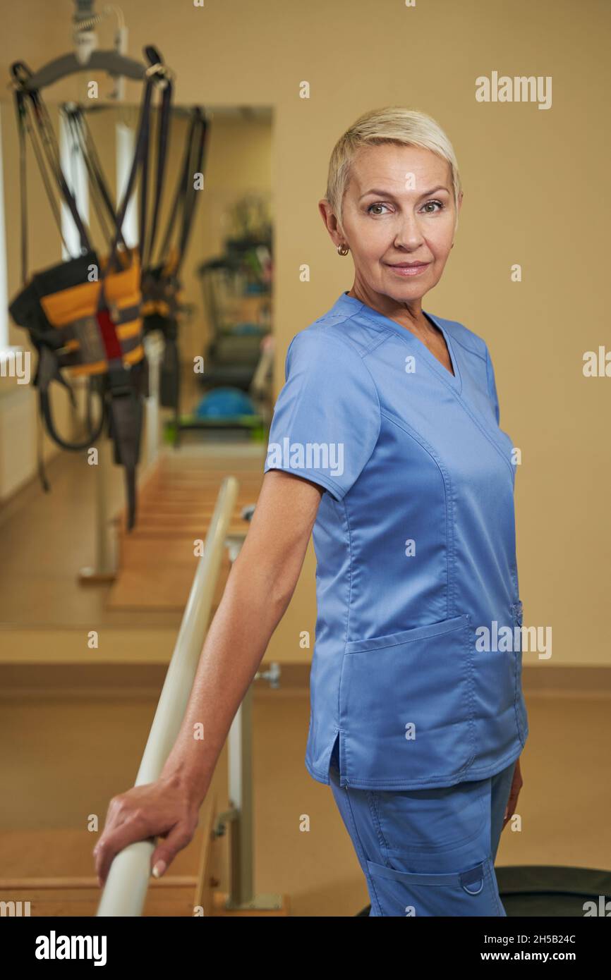 Professional female physiotherapist standing in rehabilitation center ...