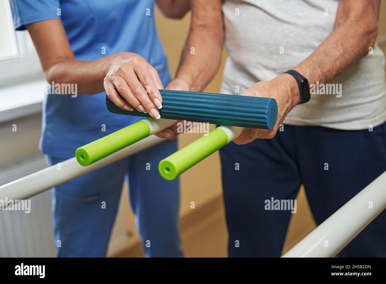 Healthcare professional helping mature patient exercising in hospital ...