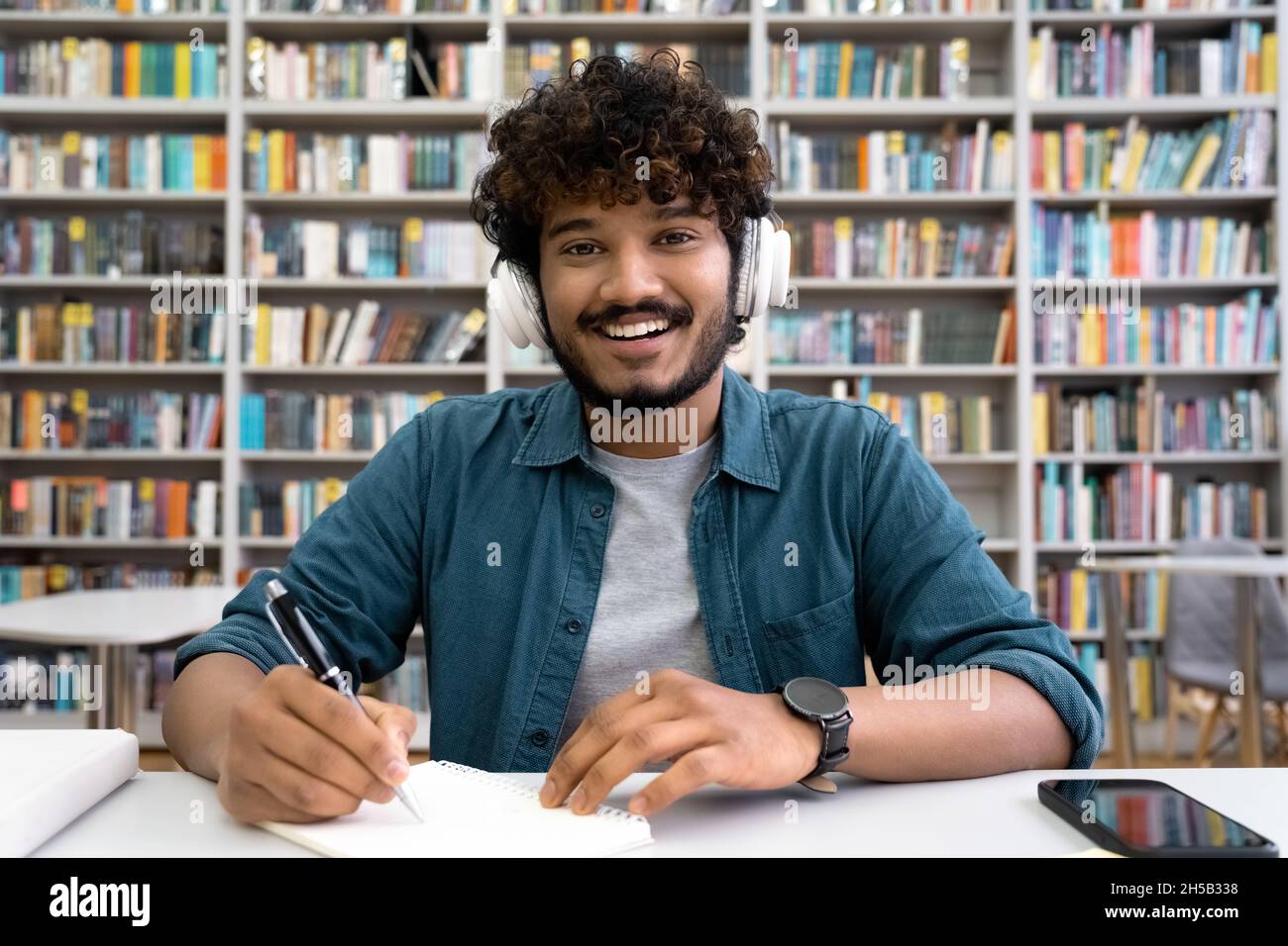 Portrait of smiling Indian student in headset looking at camera at ...