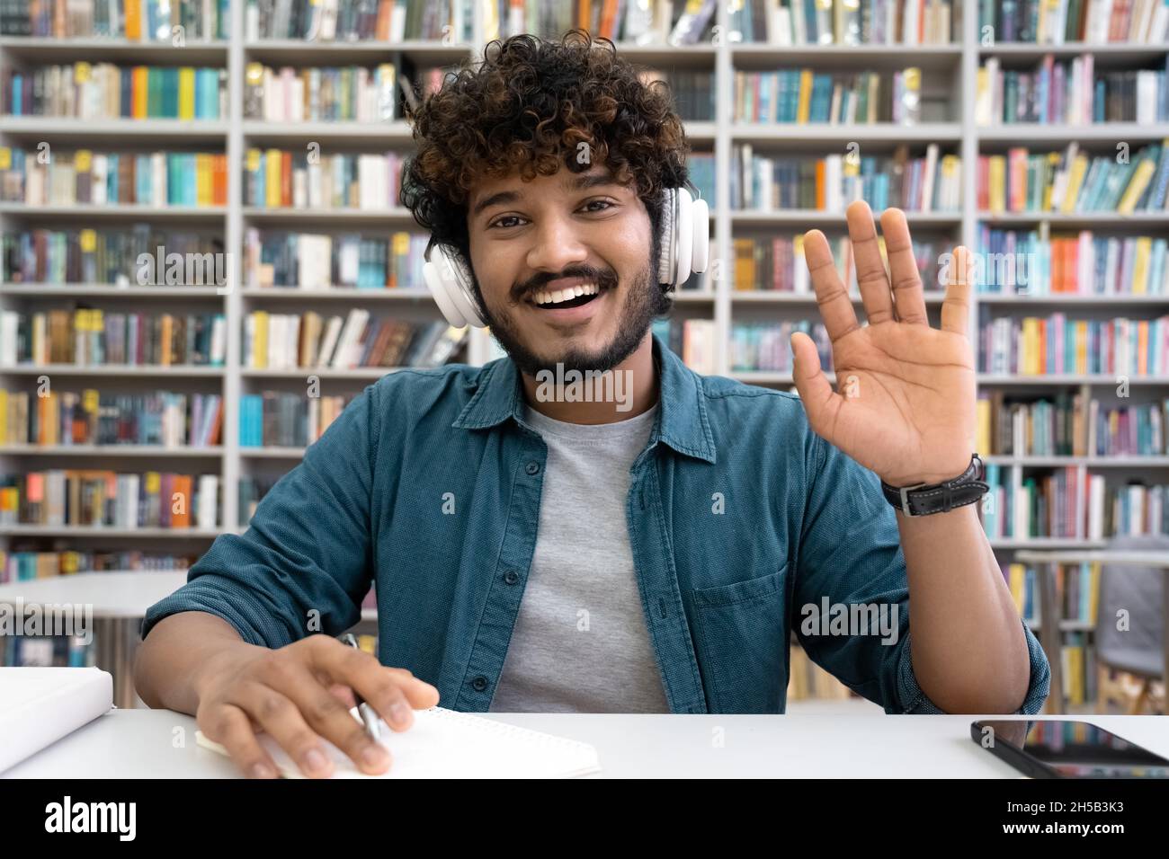 Indian student in headset greeting classmates or teacher looking at ...