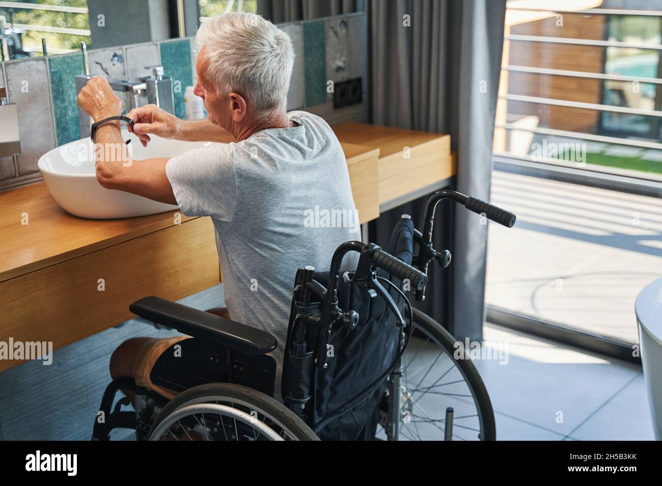 Elderly disabled person taking off smartwatch while washing hands Stock ...