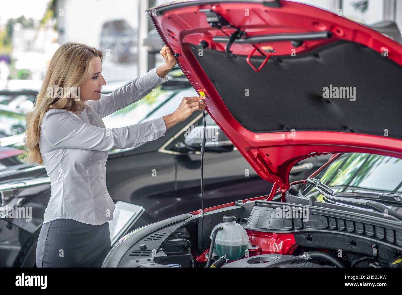 Smiling confident woman opening car hood Stock Photo - Alamy