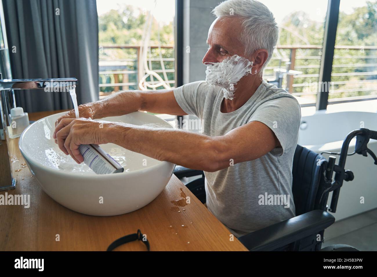 Male wheelchair user washing hands after applying shaving cream Stock ...