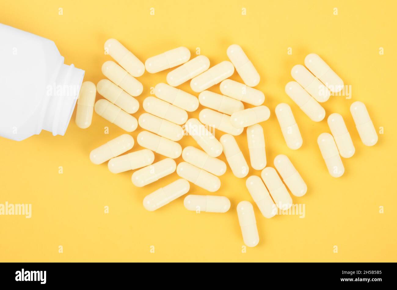 Yellow pharmaceutical medicine capsules over yellow background. White ...