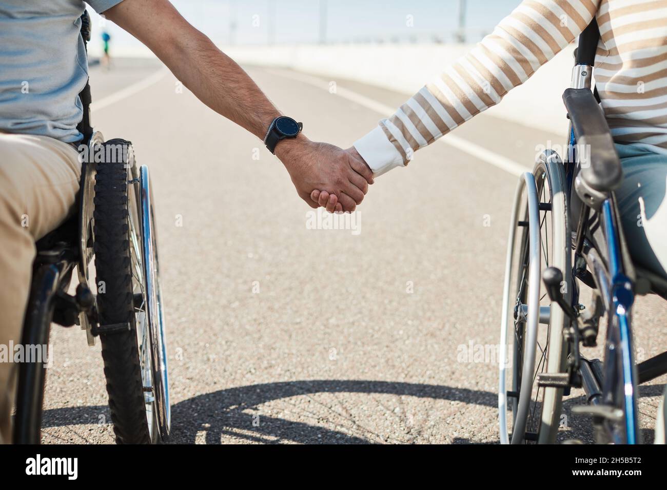Close up of couple in wheelchairs holding hands outdoors, love and ...