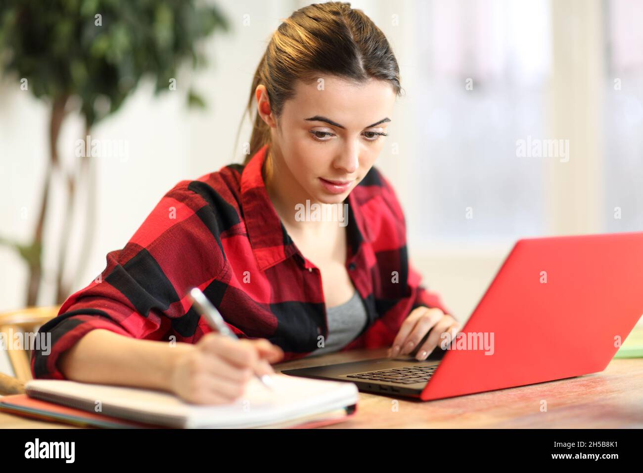 Concentrated student e-learning using laptop and taking notes at home ...