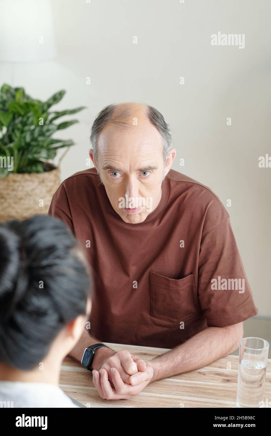 Serious senior man asking general practitioner about consequences of ...
