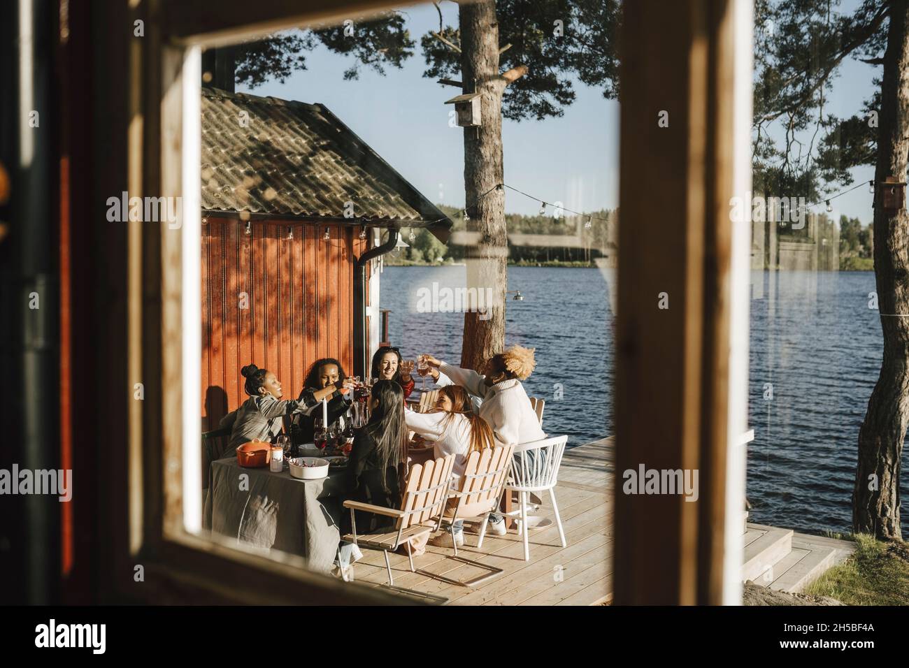 Female friends celebrating during party seen through window Stock Photo ...