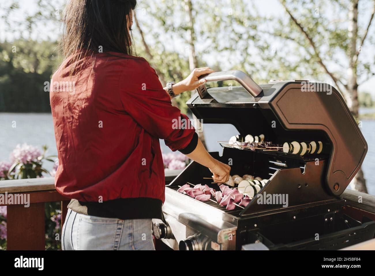 Young woman preparing food on barbecue grill during dinner party Stock ...