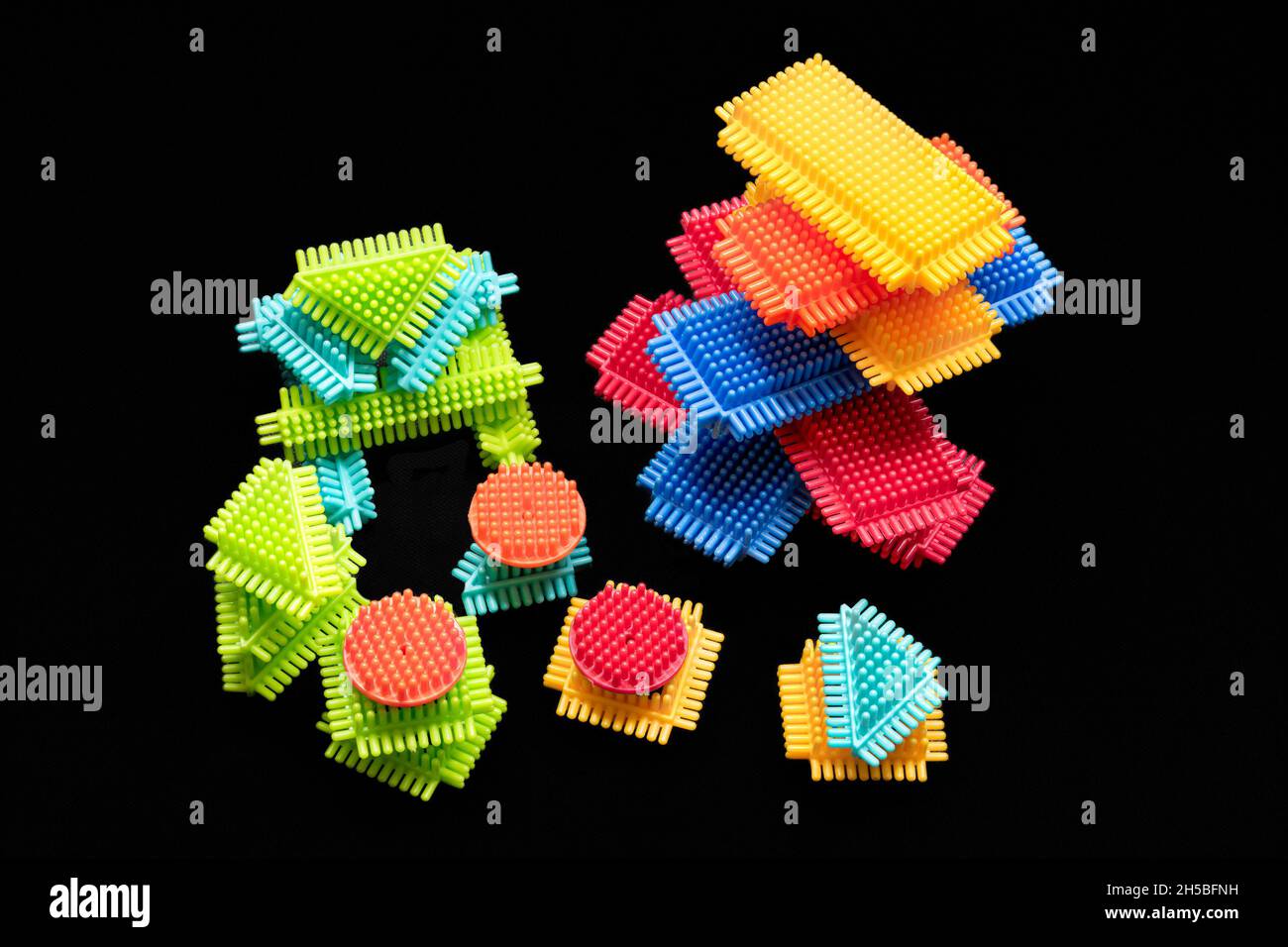 Children’s sticky block set of varying colours and shapes lade out on a dark back ground. The ...