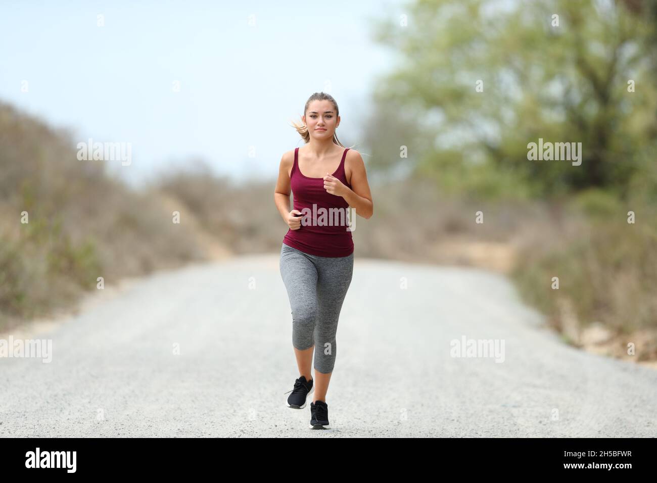 Front view full body portrait of a teenage runner running in the ...