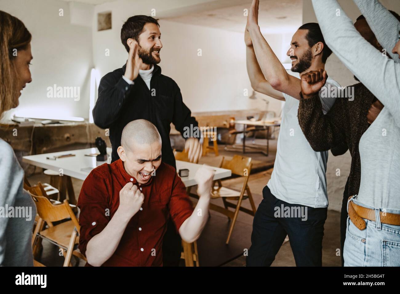 Cheerful female and male programmers celebrating success in creative ...