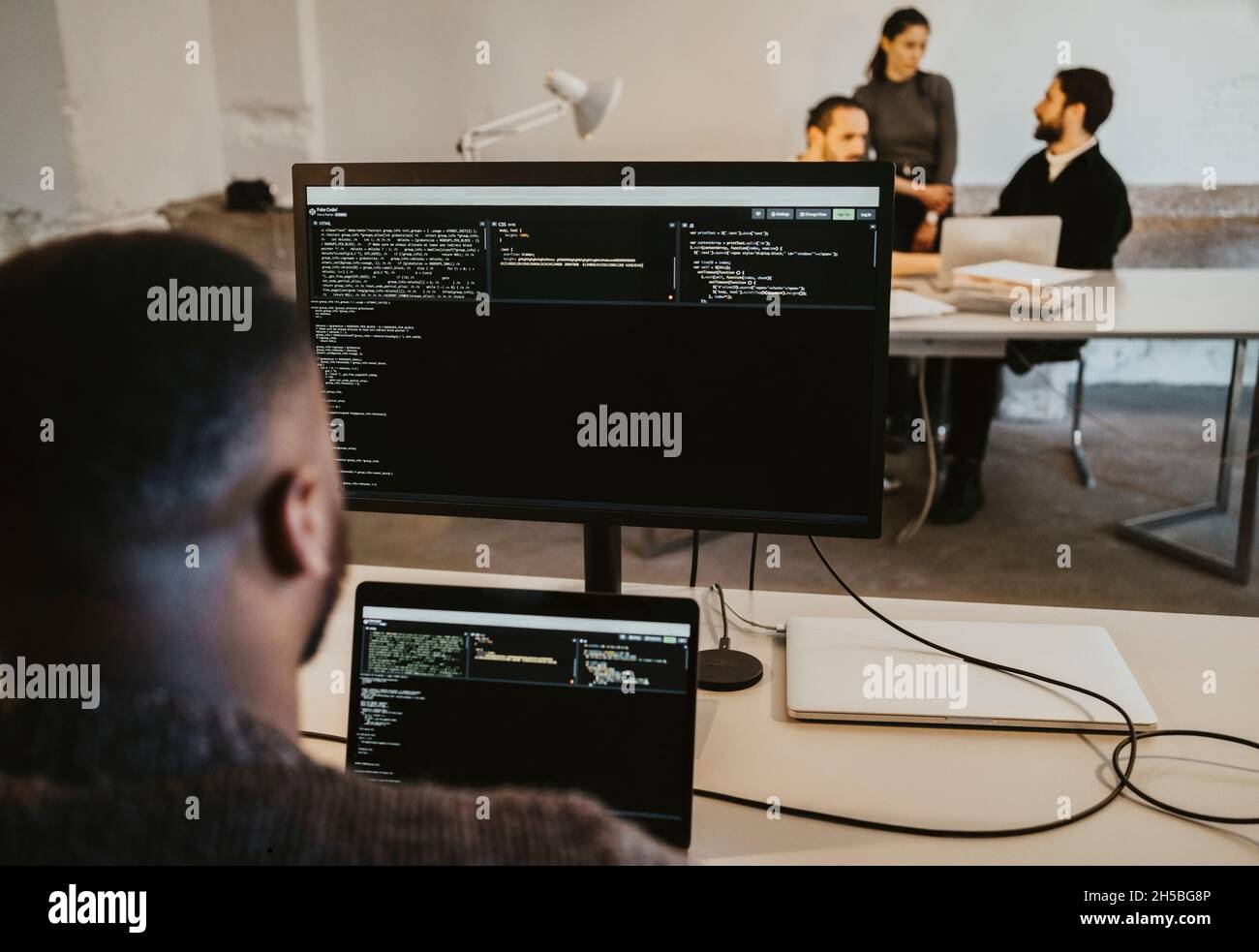 Male programmer coding on computer and laptop in startup company Stock ...