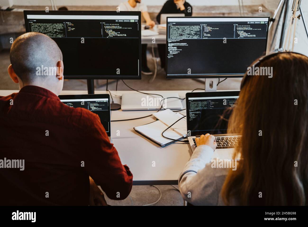 Male and female programmer doing coding over laptop in startup company ...