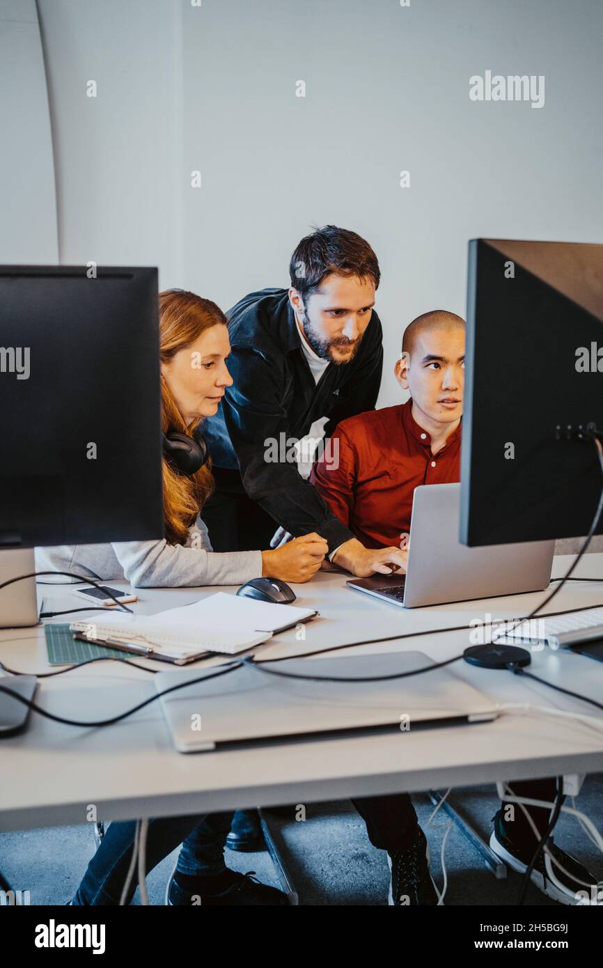 Male programmer doing coding with colleagues in startup company Stock ...