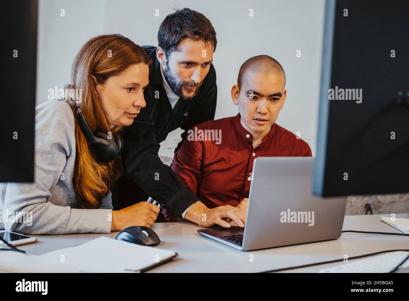 Female and male programmers concentrating while coding over laptop at ...