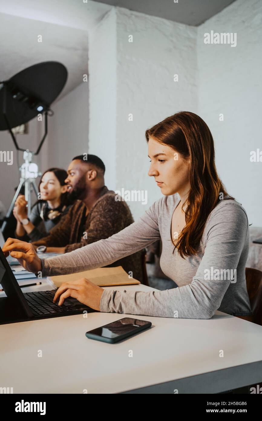 Male and female programmers working on laptop at desk in office Stock ...