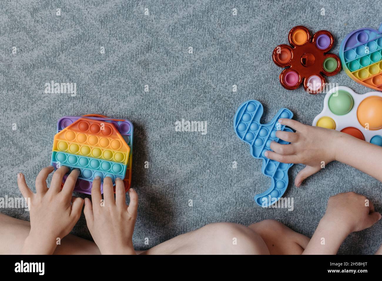 View from above to children playing with pop it toys. Happy childhood ...