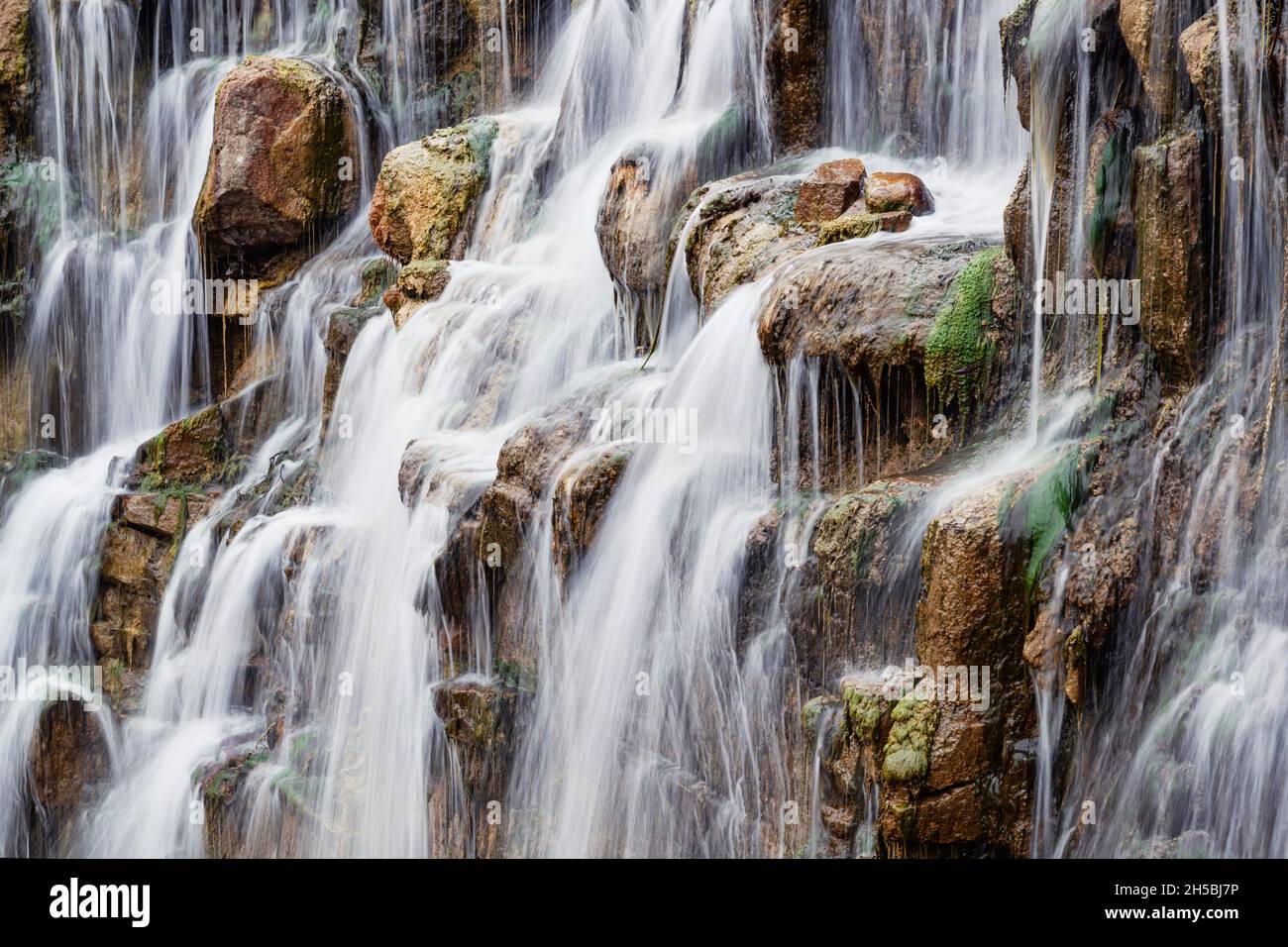Powerful waterfall with many water streams running around rocks and ...